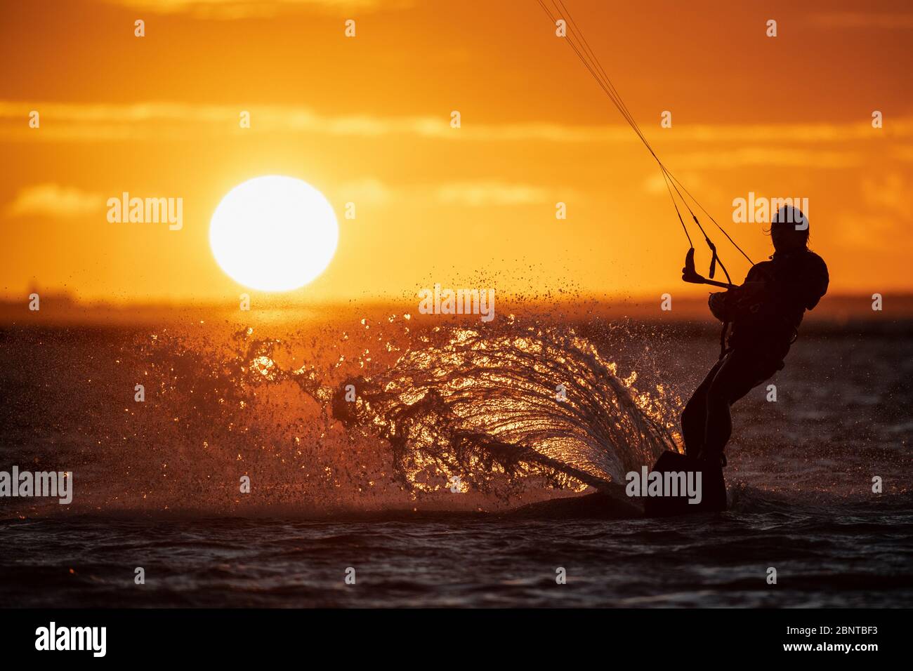 Norddeich, Germany. 15th May, 2020. A kitesurfer pulls a wave behind ...
