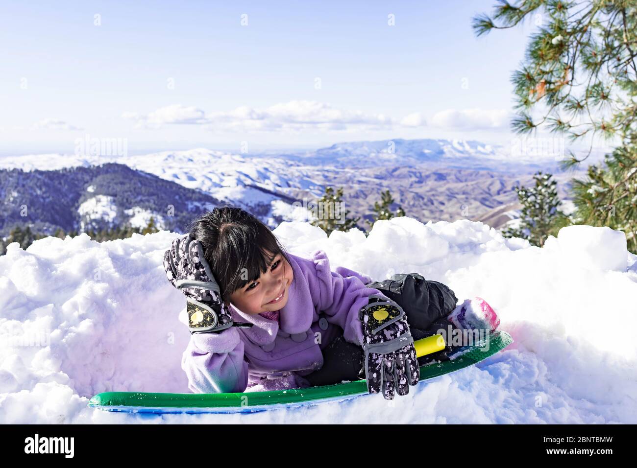 Female child while sitting on a snow board and playing with snow Stock ...