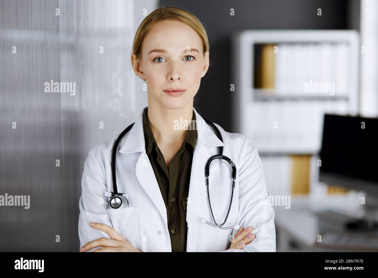 Friendly smiling female doctor standing in clinic. Portrait of friendly ...