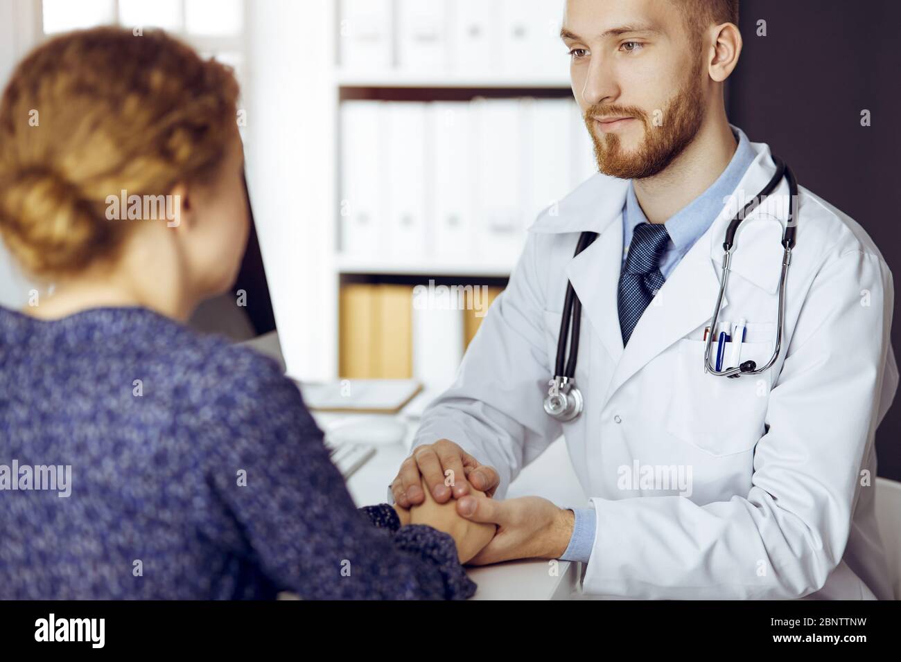 Friendly red-beard doctor reassuring his female patient. Medical ethics ...