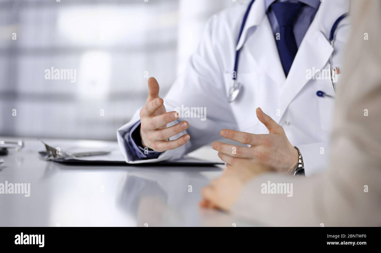 Unknown male doctor and patient woman discussing something while ...