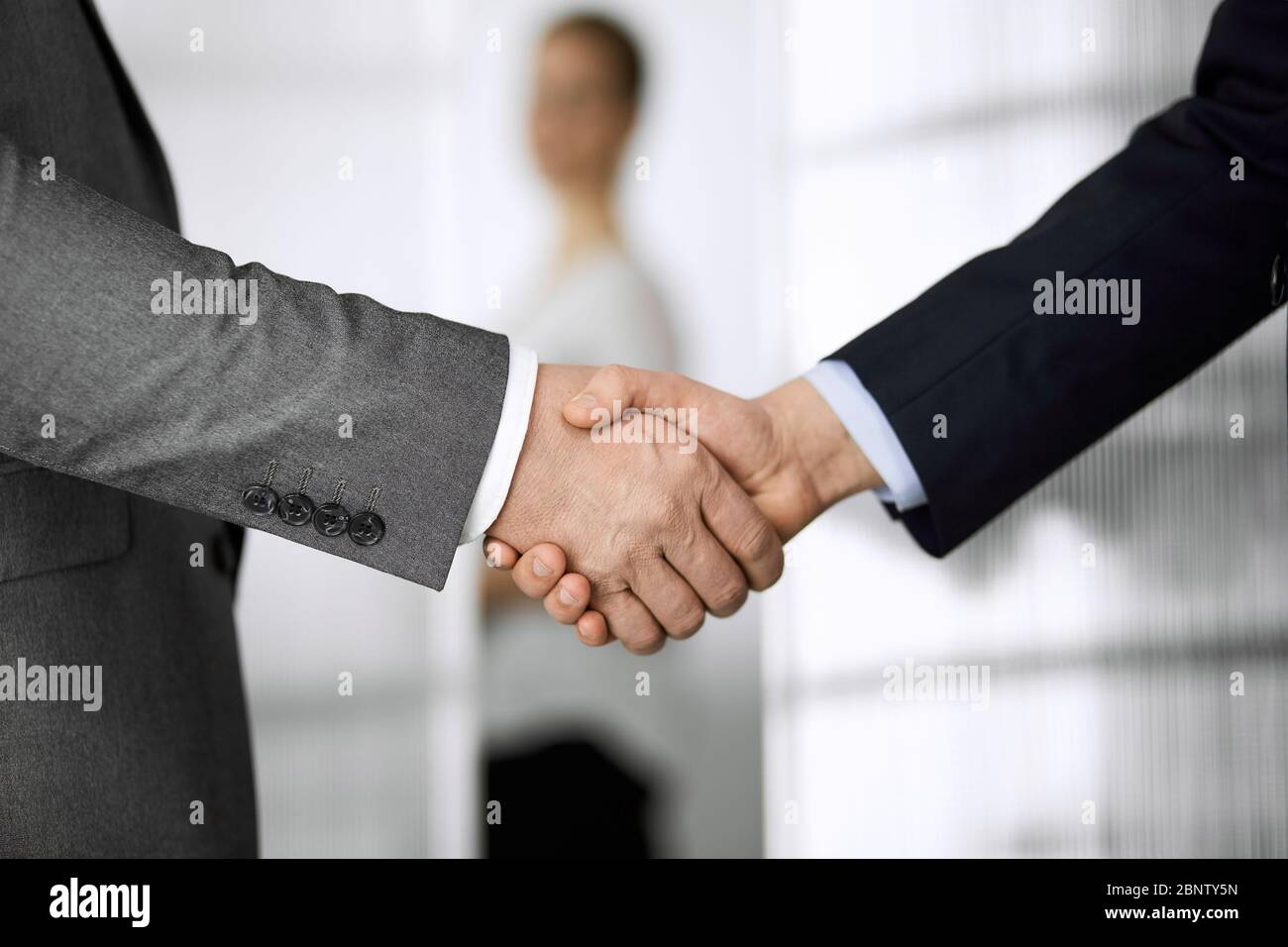 Business people in office suits standing and shaking hands, close-up ...