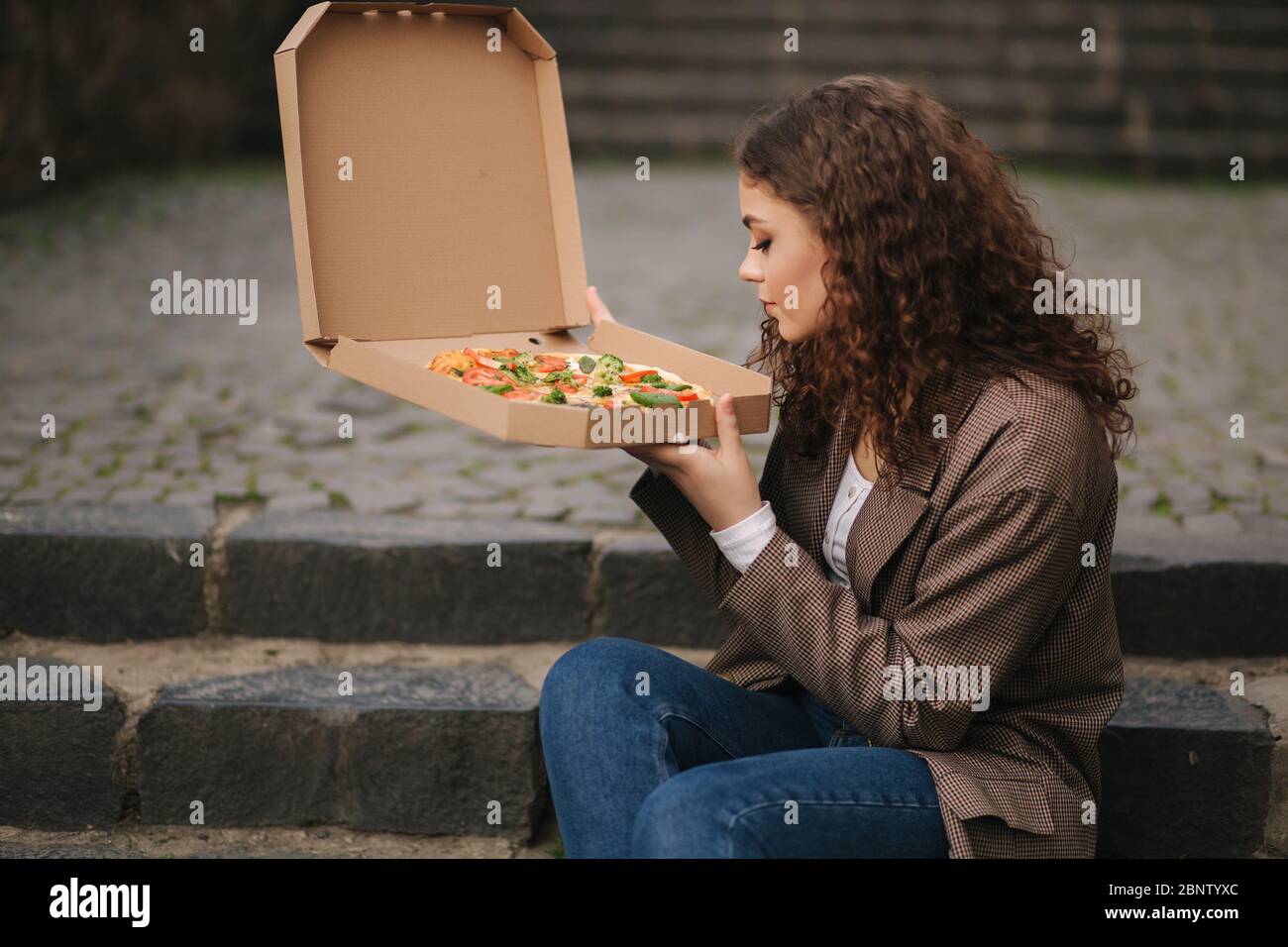 Woman open pizza box outdoors. Female hold open pizza box and smells ...