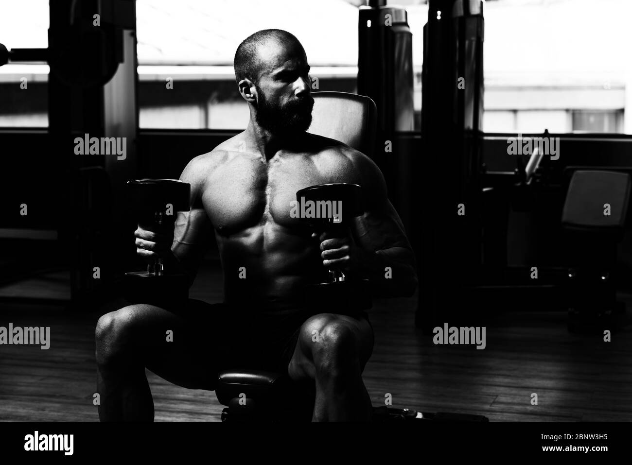 Healthy Man Working Out Shoulders In A Dark Gym Stock Photo - Alamy
