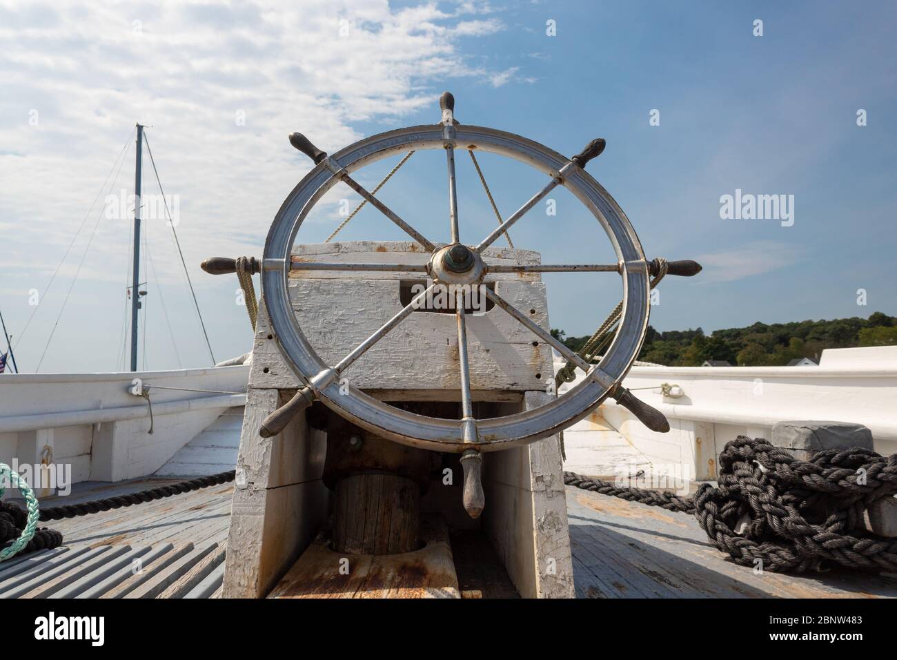 Ship's wheel helm of an old sailing vessel, boat deck with rope rigging ...