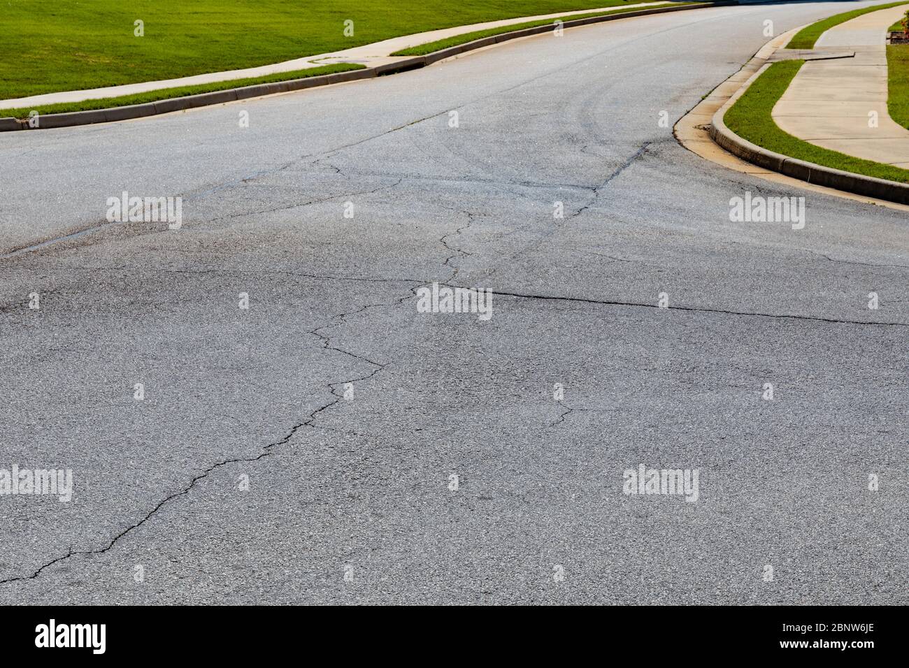 Expansive residential street intersection with asphalt, sidewalks and ...
