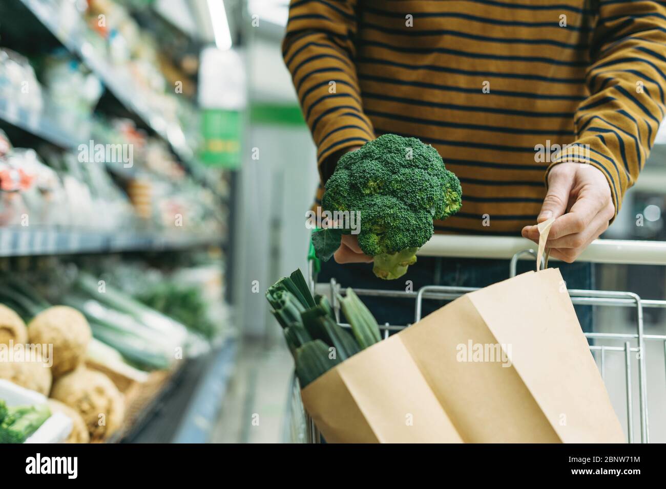 Man in the vegetable department at supermarket puts broccoli in the ...