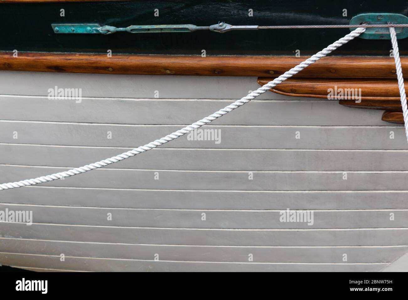Exterior hull of an old wooden boat, green patina hawsehole with ropes ...