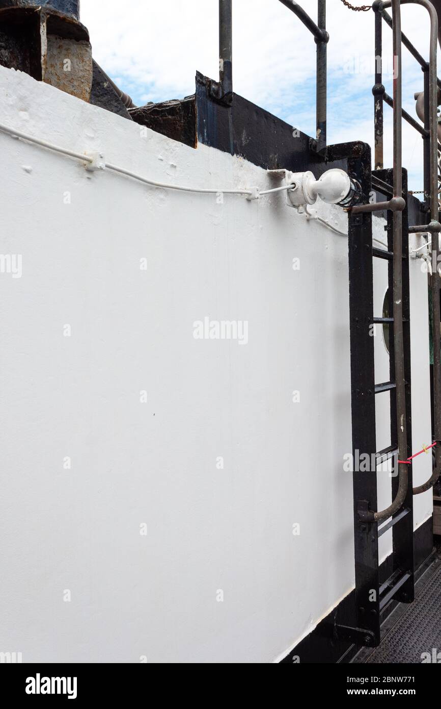 Interior wall of an old metal ship, black painted ladder with white ...