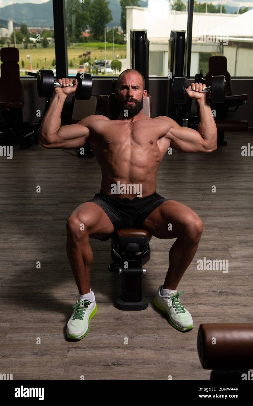 Healthy Man Working Out Shoulders In A Dark Gym Stock Photo - Alamy