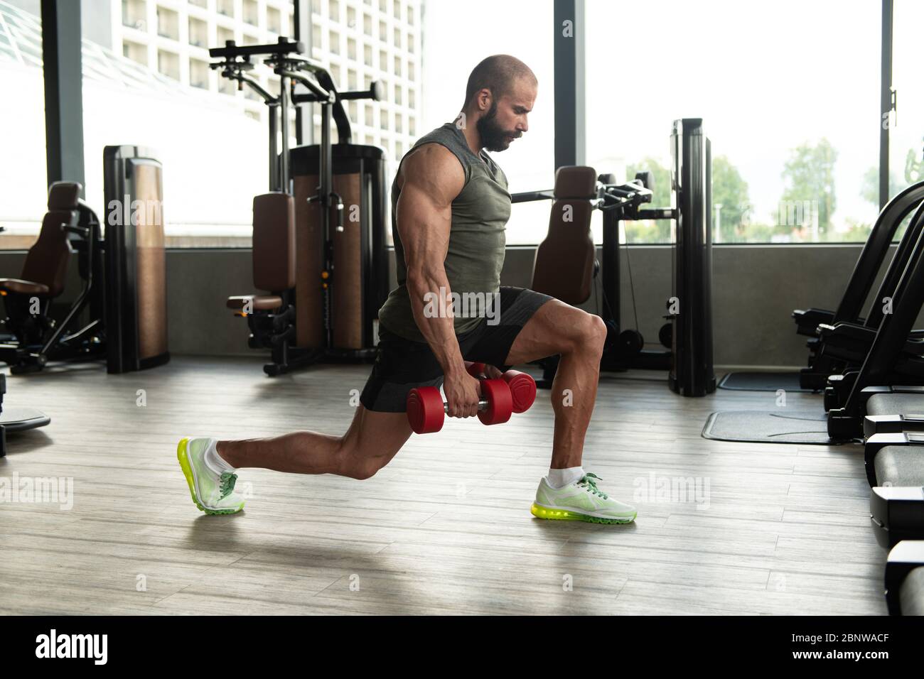 Strong Man In The Gym Exercising Legs With Dumbbells - Muscular ...