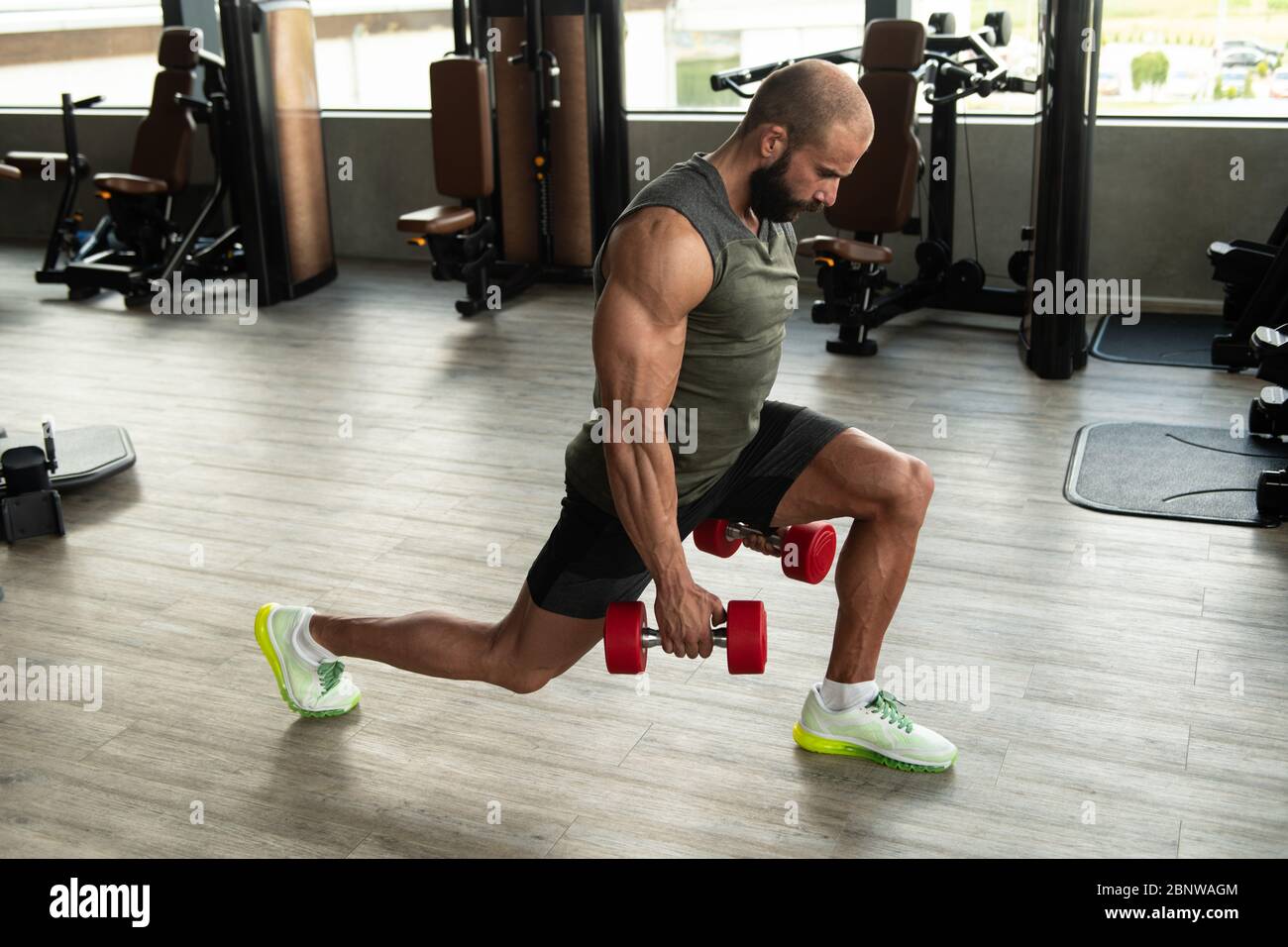 Strong Man In The Gym Exercising Legs With Dumbbells - Muscular ...