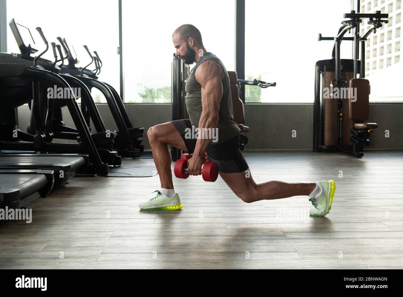 Strong Man In The Gym Exercising Legs With Dumbbells - Muscular ...