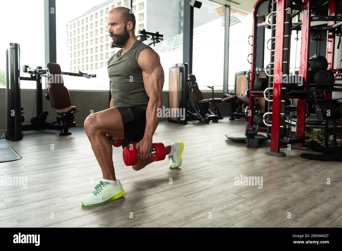 Strong Man In The Gym Exercising Legs With Dumbbells - Muscular ...