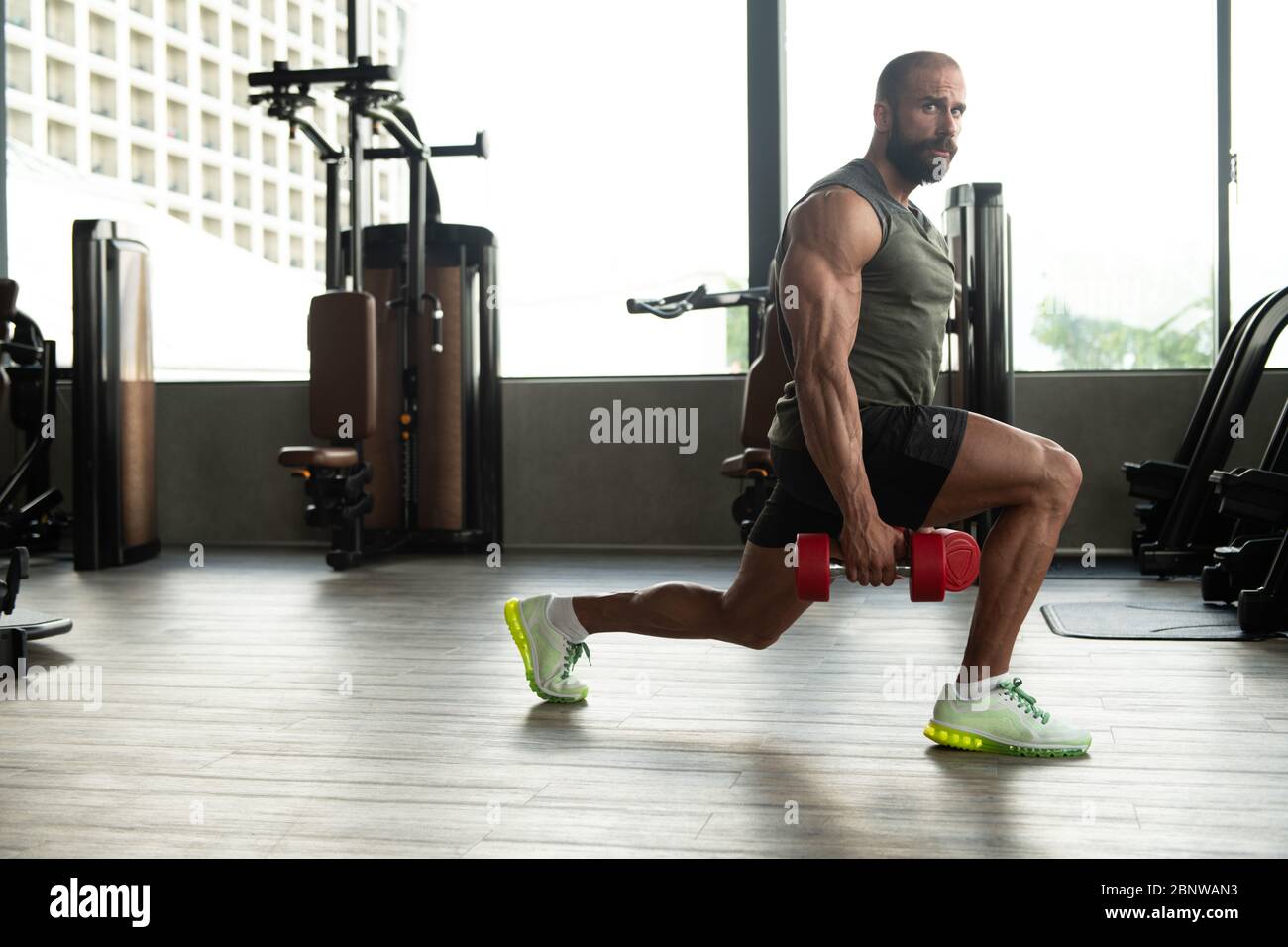 Strong Man In The Gym Exercising Legs With Dumbbells - Muscular ...