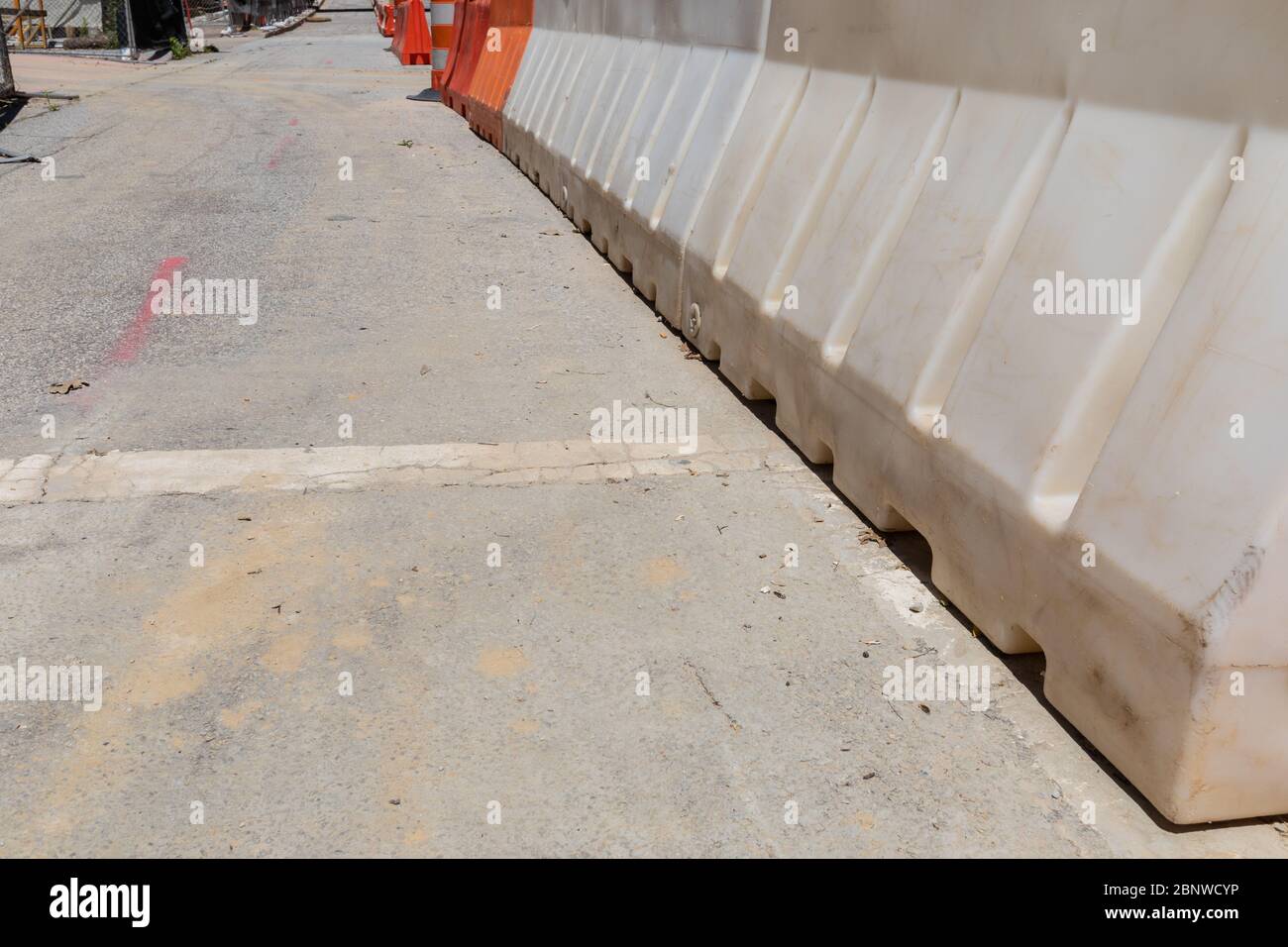 Long view down a row of hard plastic orange and white traffic barriers ...