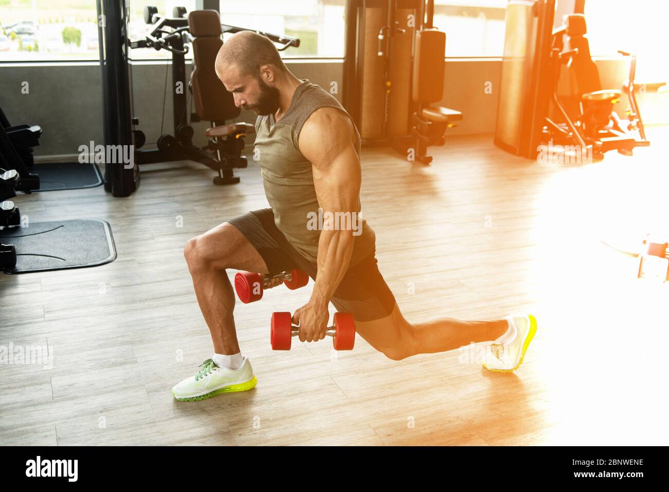 Strong Man In The Gym Exercising Legs With Dumbbells - Muscular ...