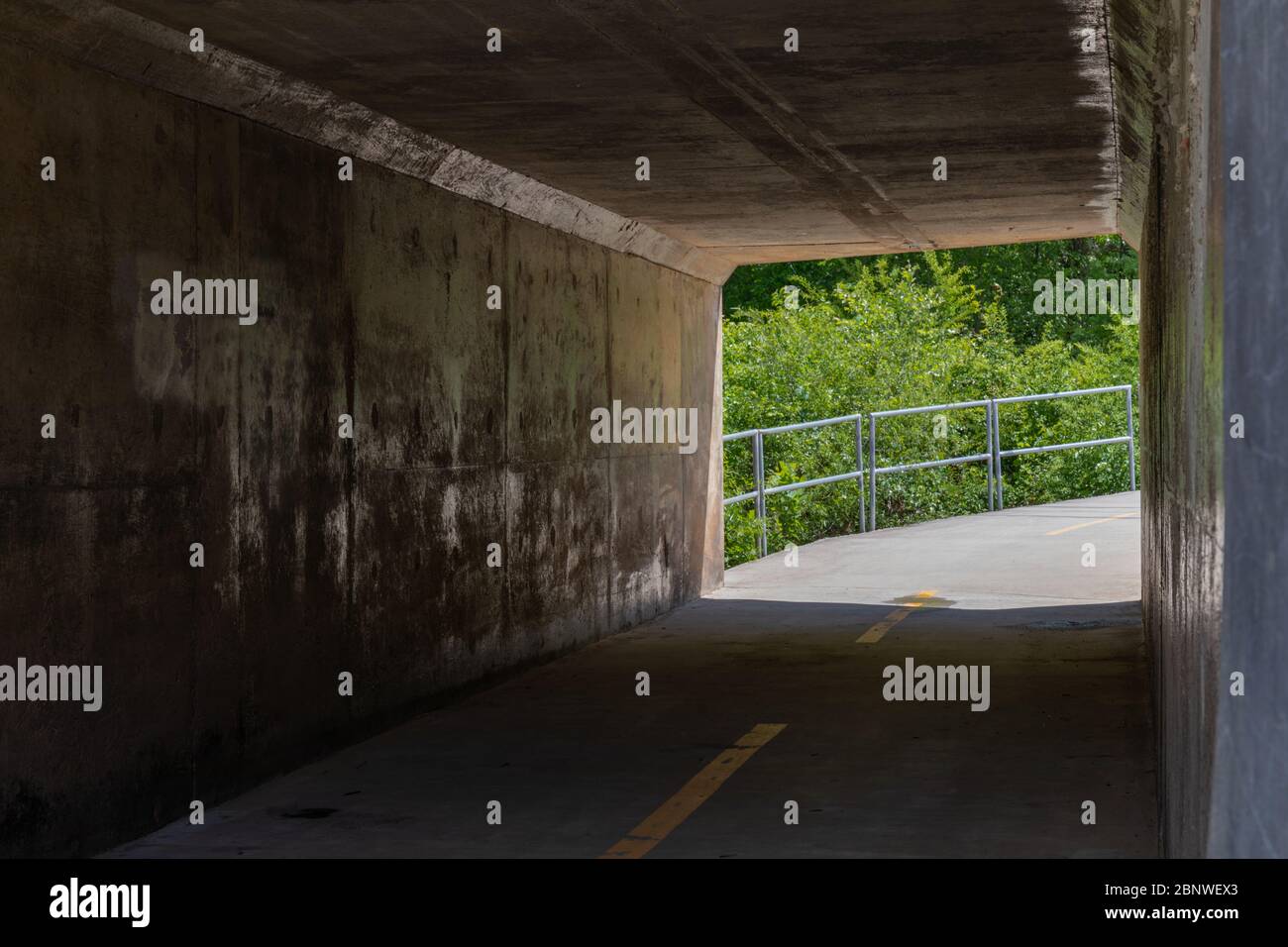 Bike path tunnel under roadway, sharp curve and railing beyond ...