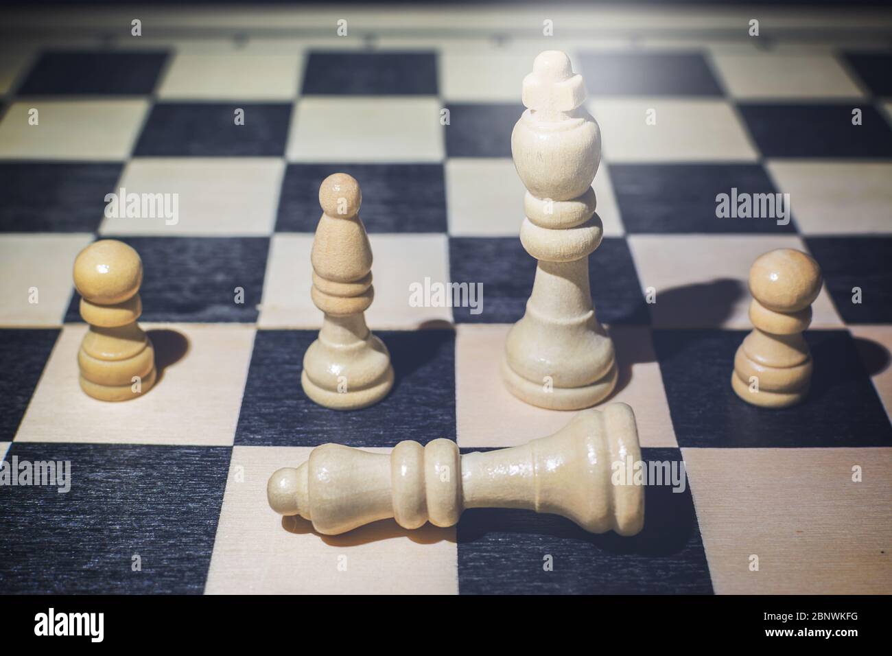 White queen fallen on the chessboard and behind her the king and other ...
