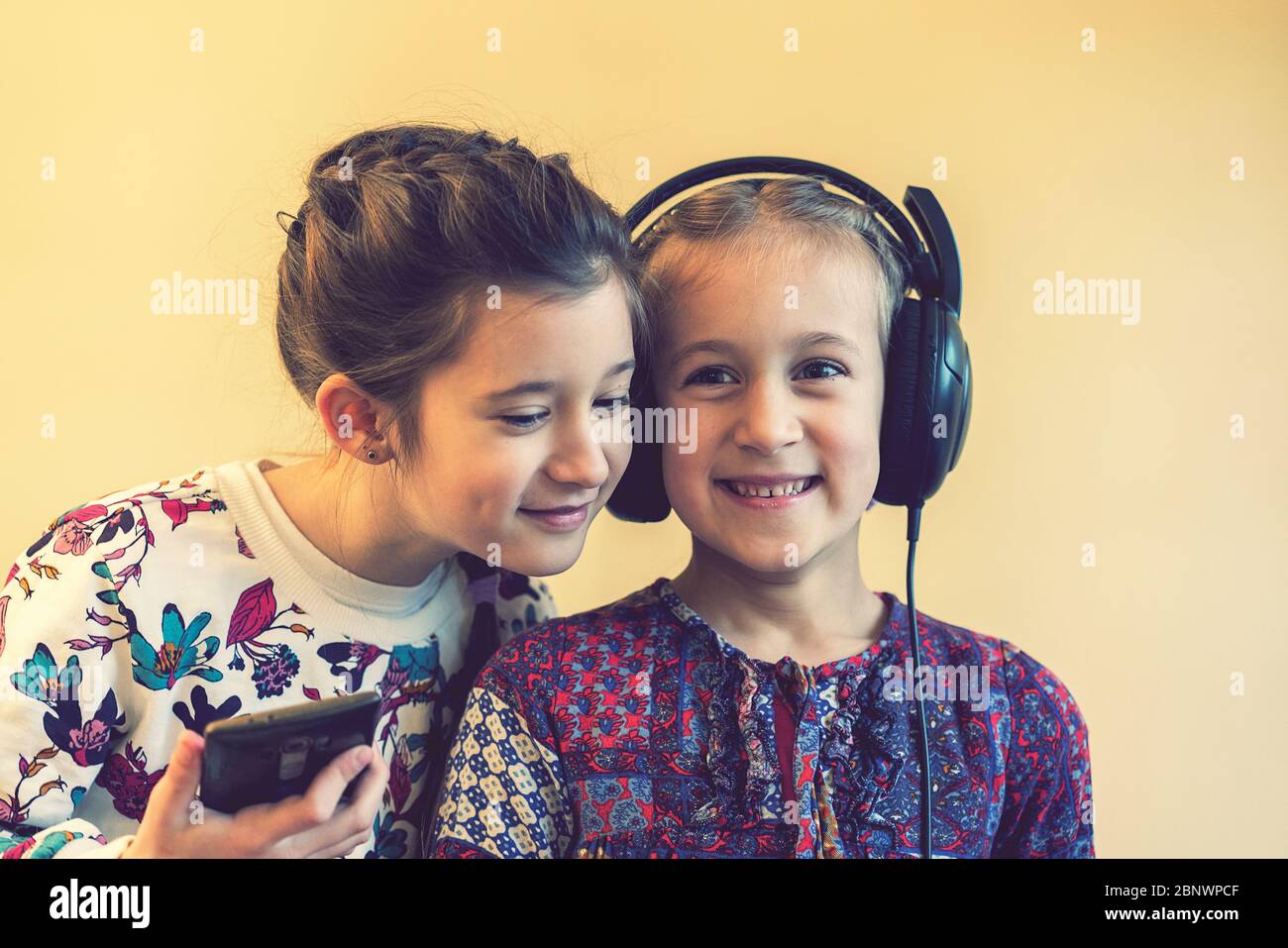 Two little happy girls together listening to music. Two little girls ...