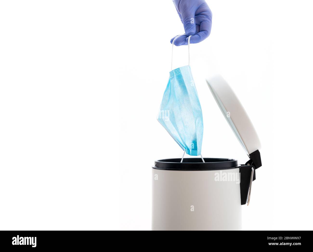 Hand with glove throwing away a protective face mask to the garbage ...