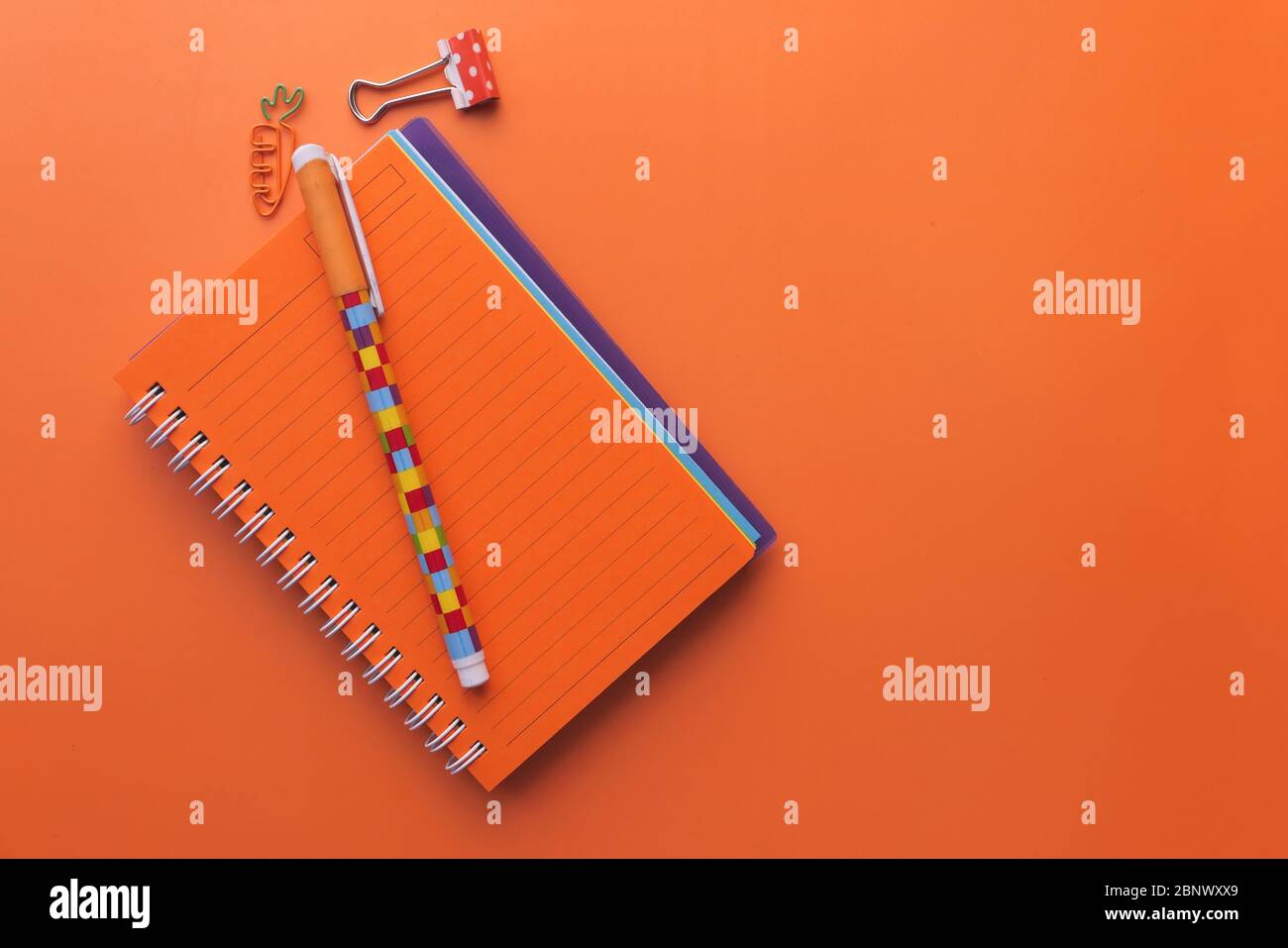 open colorful notepad and pens on orange background Stock Photo - Alamy