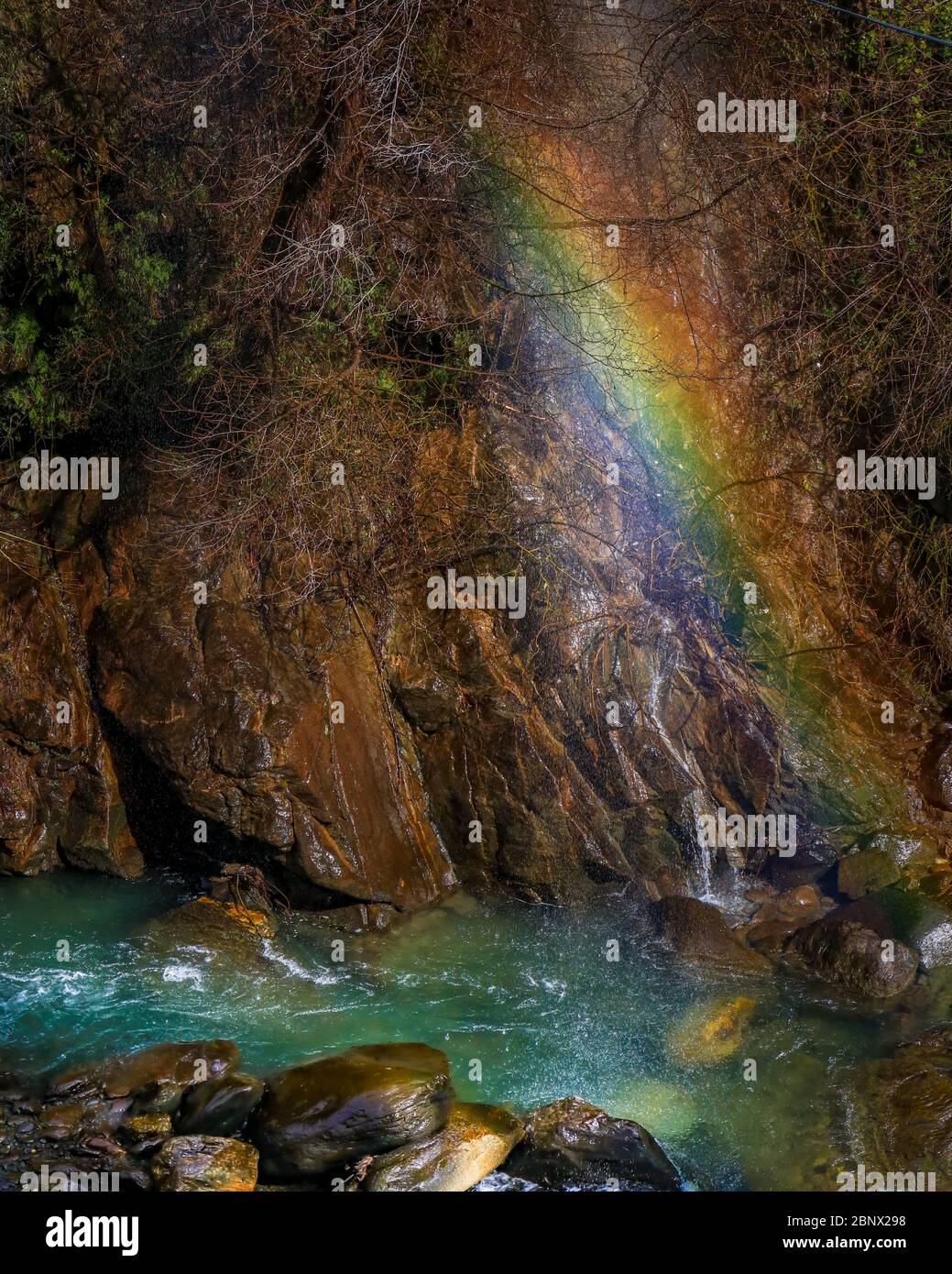 A Rainbow Forms due to Sunlight in a Waterfall which has Heavenly Green ...