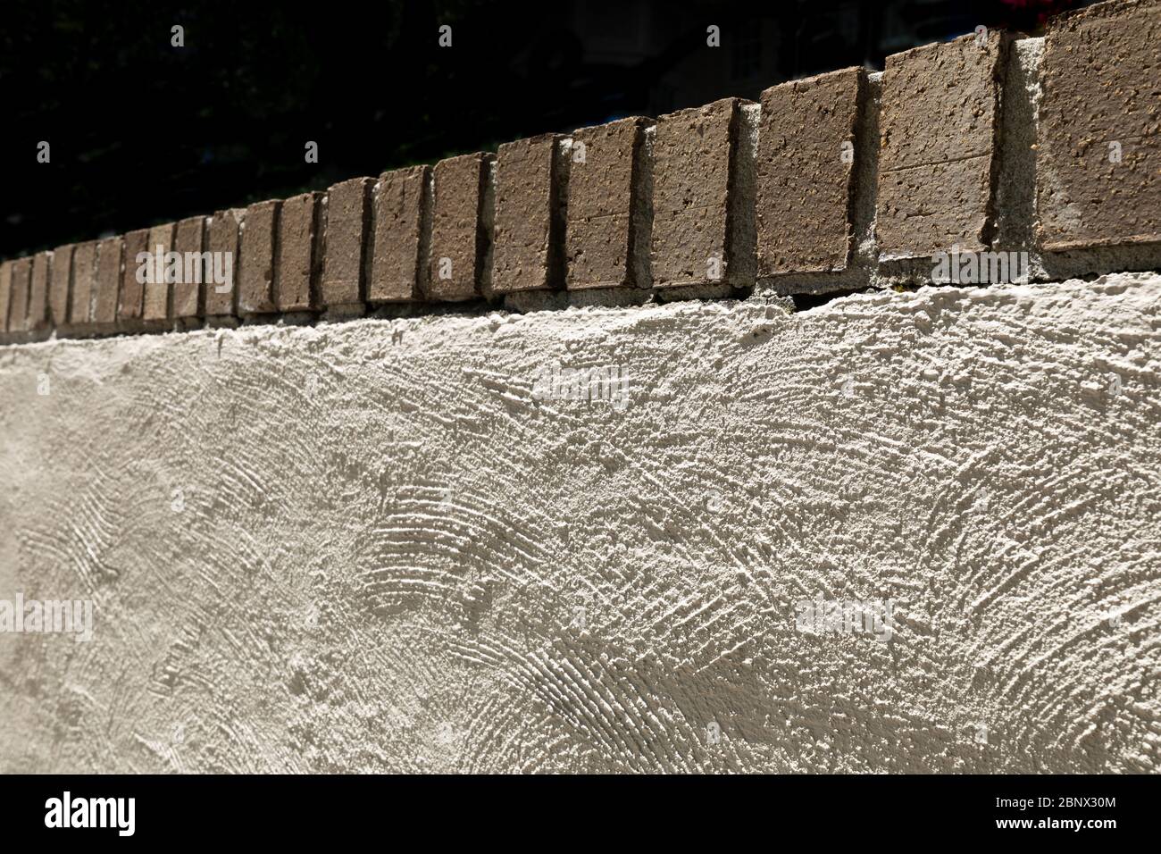 Stucco wall topped with brown brick, trowel texture copy space ...