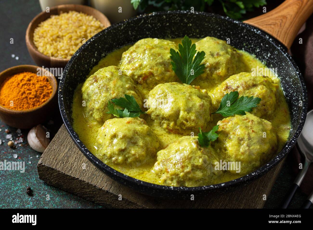 Meatballs with bulgur in sour cream and turmeric sauce in a pan on a ...