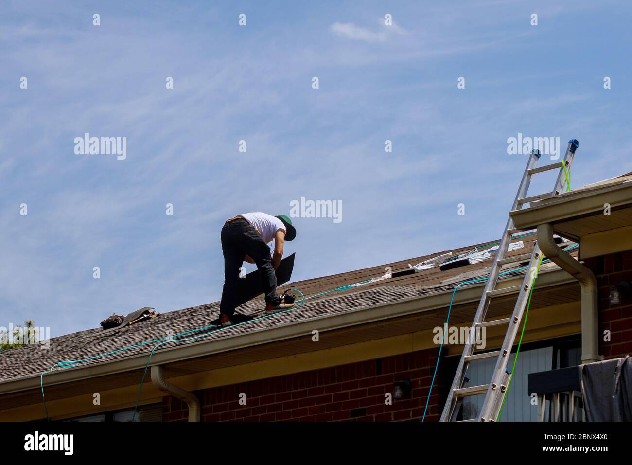 Roof repair, worker with replacing gray tiles shingles on house being ...