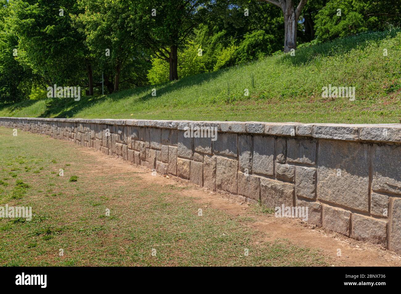 Long low rusticated stone block retaining wall in an outdoor park ...