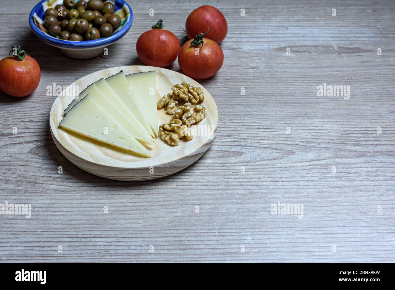 typical spanish tapas of aged manchego cheese and olives on a wooden ...