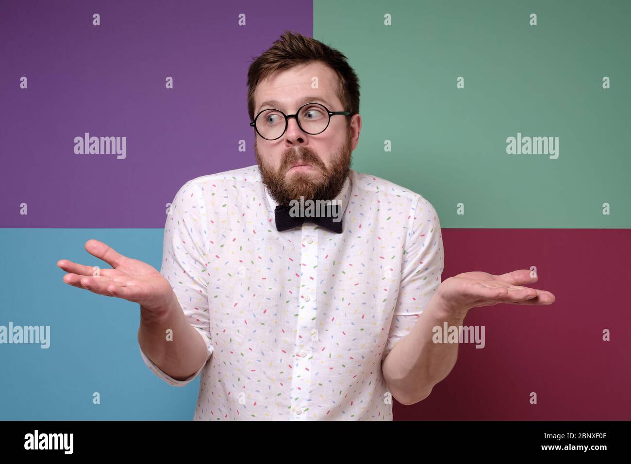 Funny man with an innocent and embarrassed expression shrugs and ...