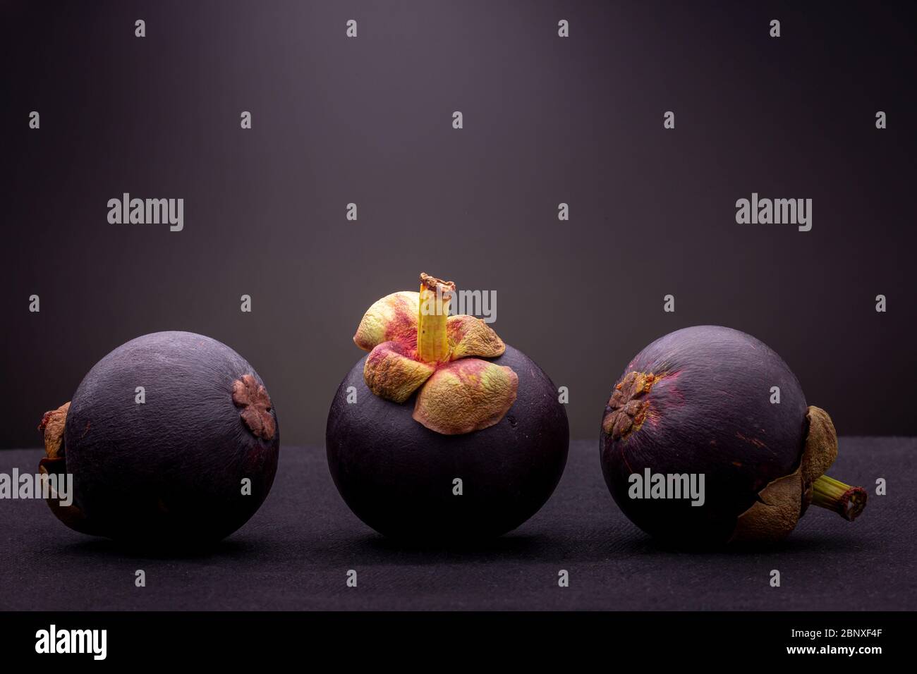 Spotlight on three specimen of the purplish-red exotic Mangosteen fruit ...