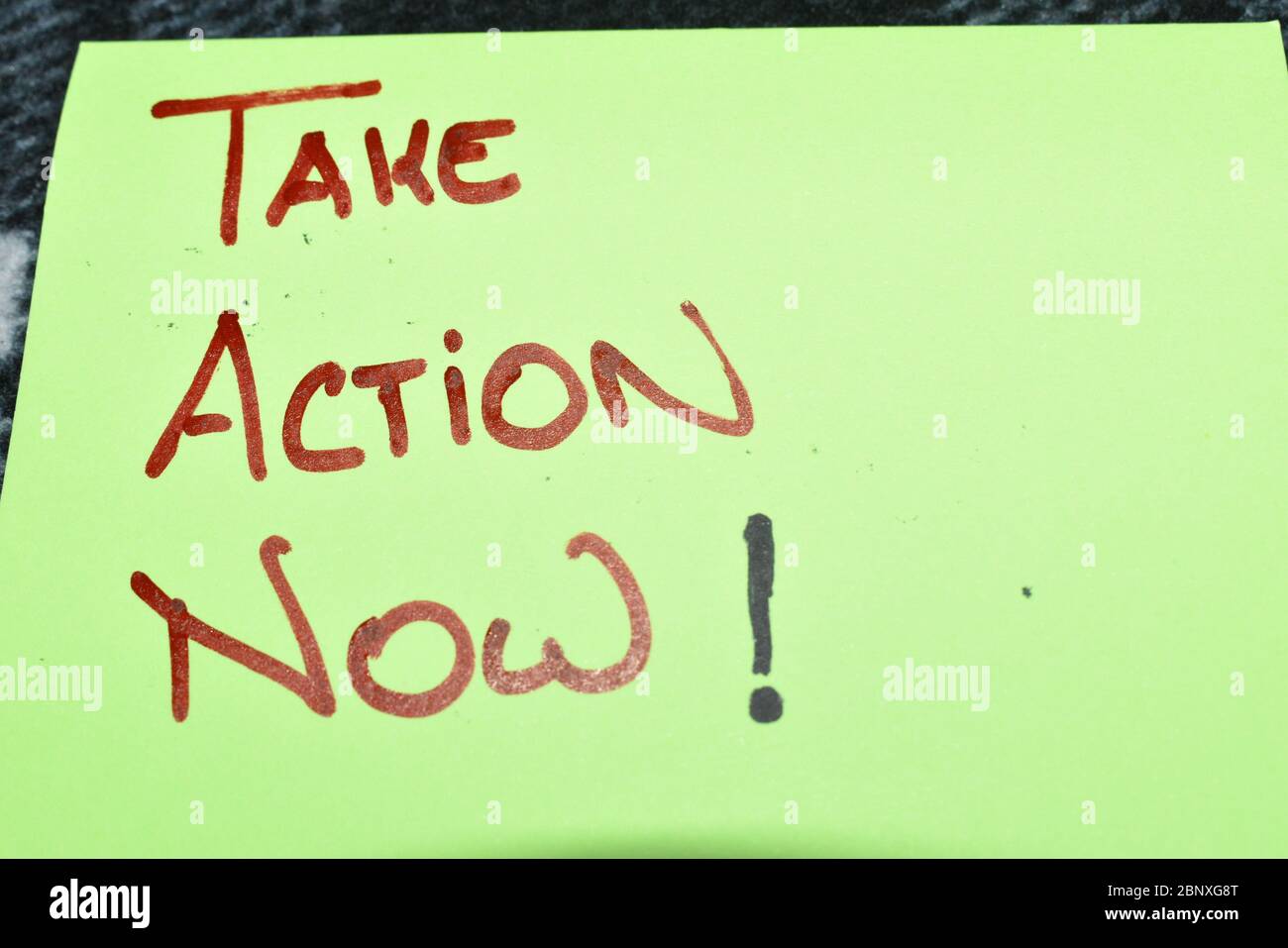 Close up of a fluorescent green color post-it note.The words "Take ...