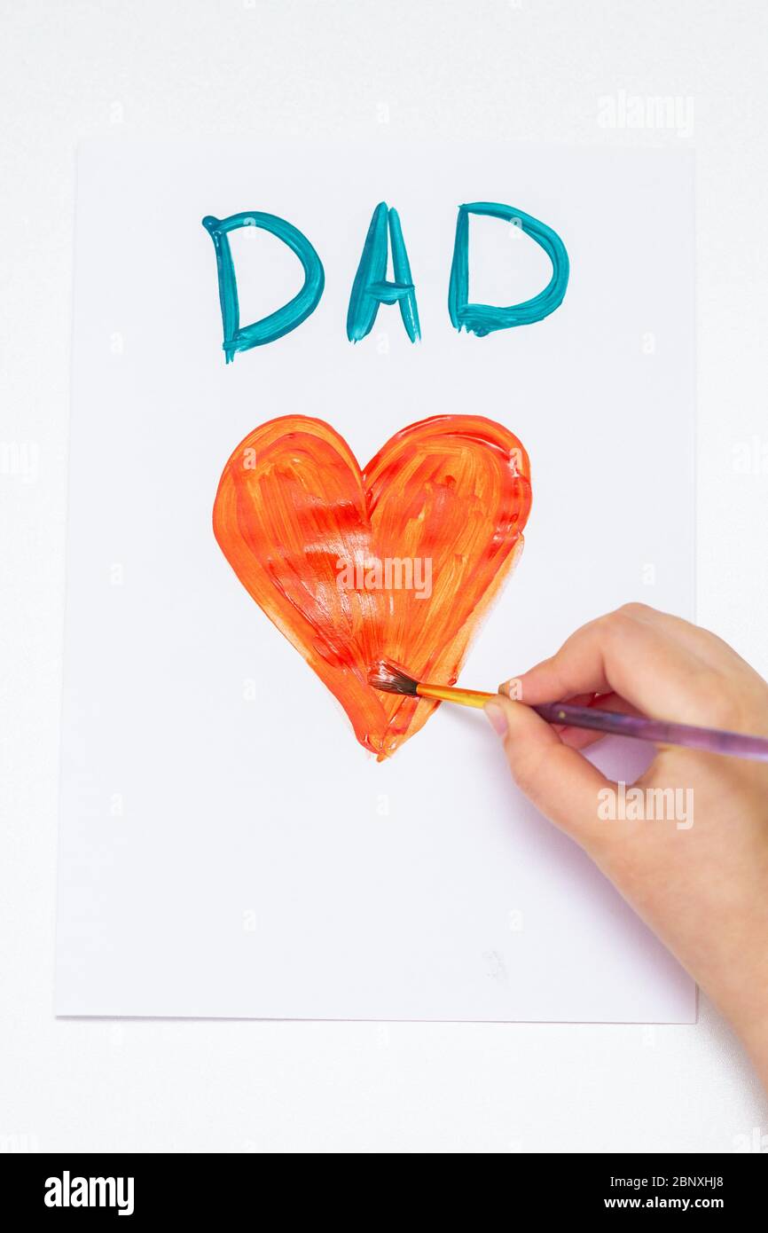 Top view of hand of child drawing red heart with word Dad greeting card ...
