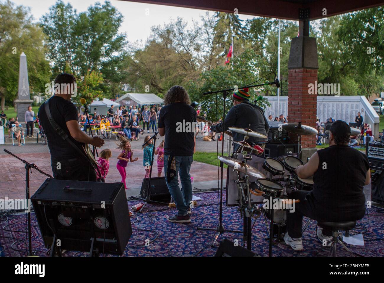 Rock band performing outdoorss, with yong kids dancing to the music ...