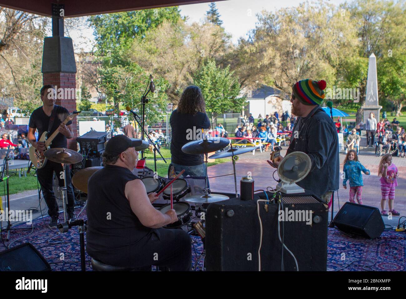 Rock band performing outdoorss, with yong kids dancing to the music ...