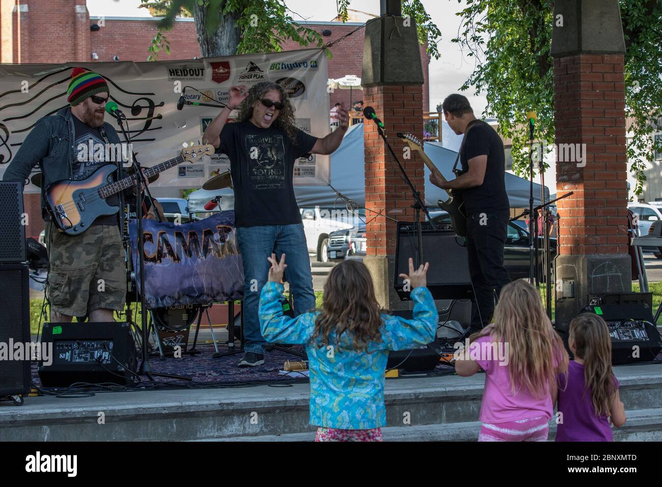 Rock band performing outdoorss, with yong kids dancing to the music ...