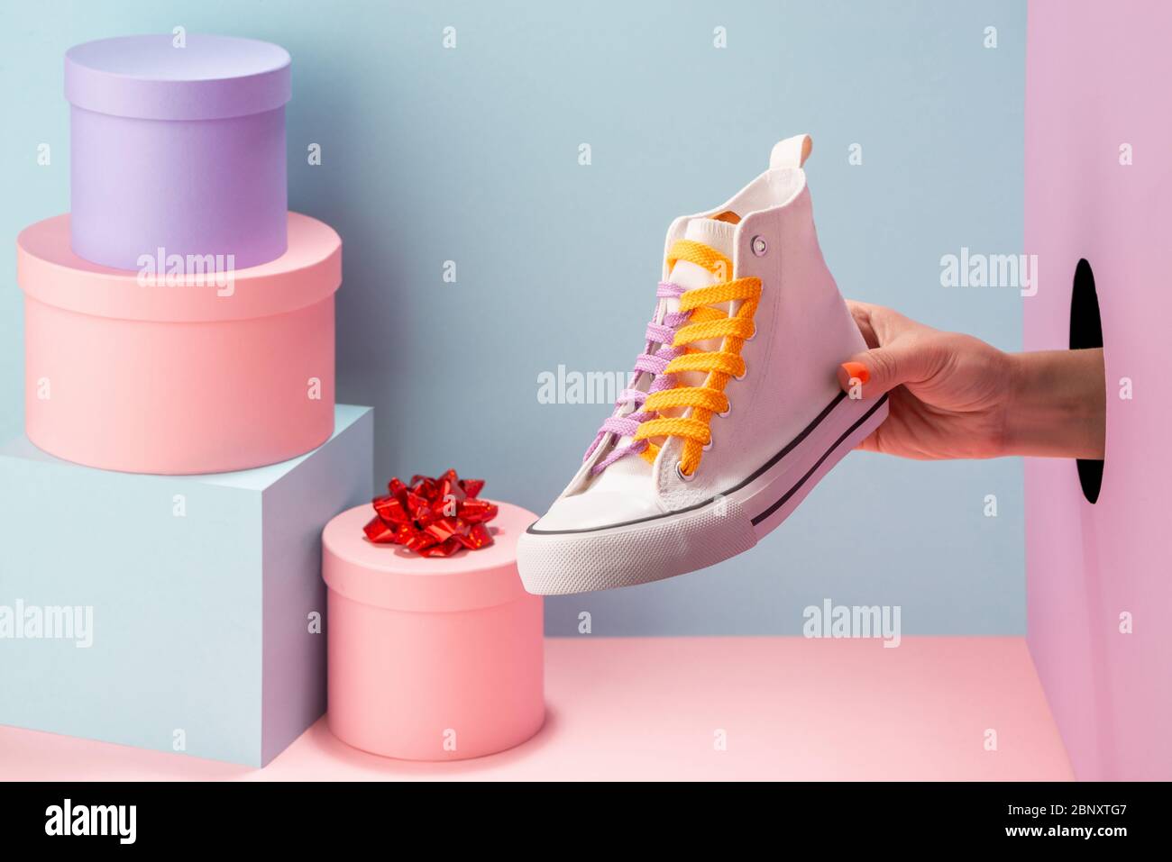 Woman's hand holding a sneaker with colorful shoelaces Stock Photo - Alamy