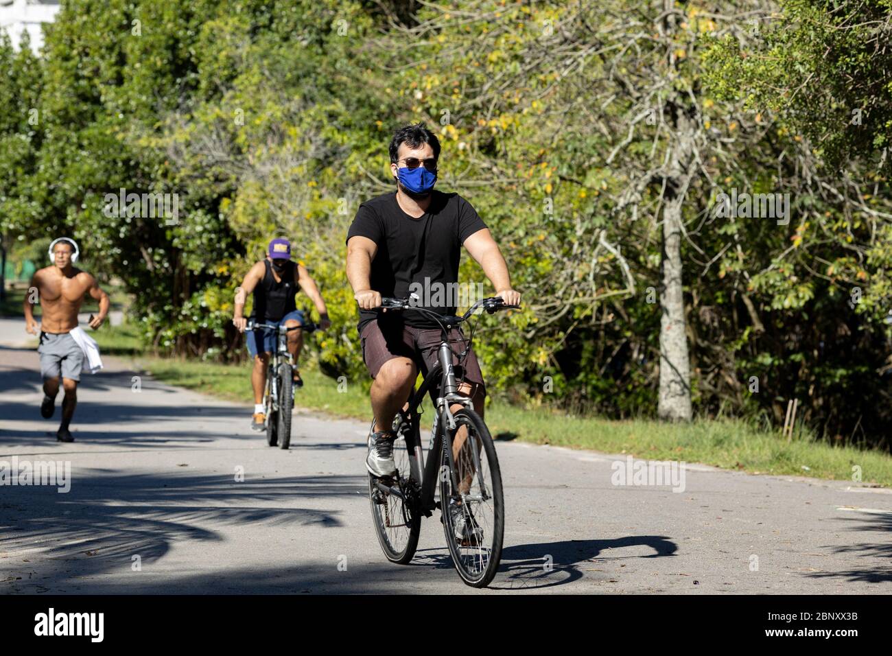 People riding their bike and run exercising in a city park during the ...
