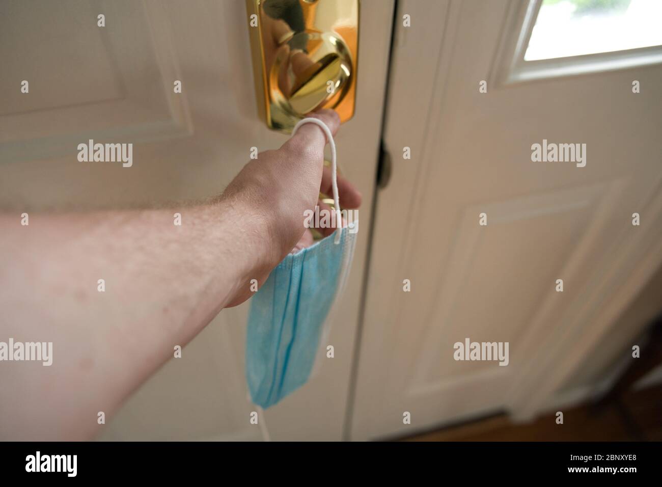 Hand holding facemask opening door during coronavirus. Mask for social ...