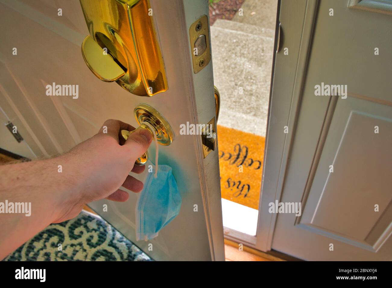 Hand opening door wearing mask as a reminder to wear masks when outside ...