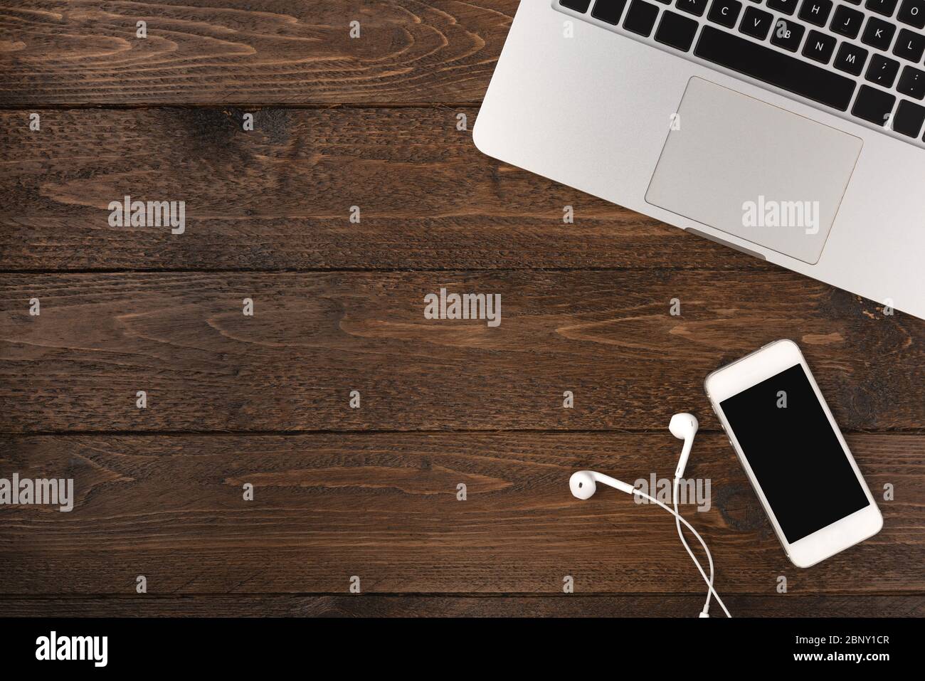 Laptop and smartphone on Vintage Wooden desktop in modern office with ...