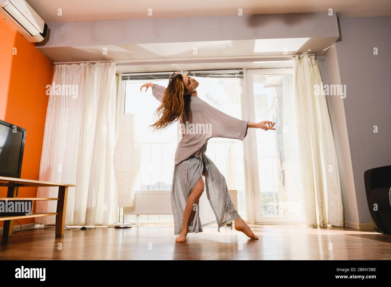Beautiful artistic girl dancer spinning around at living room during ...