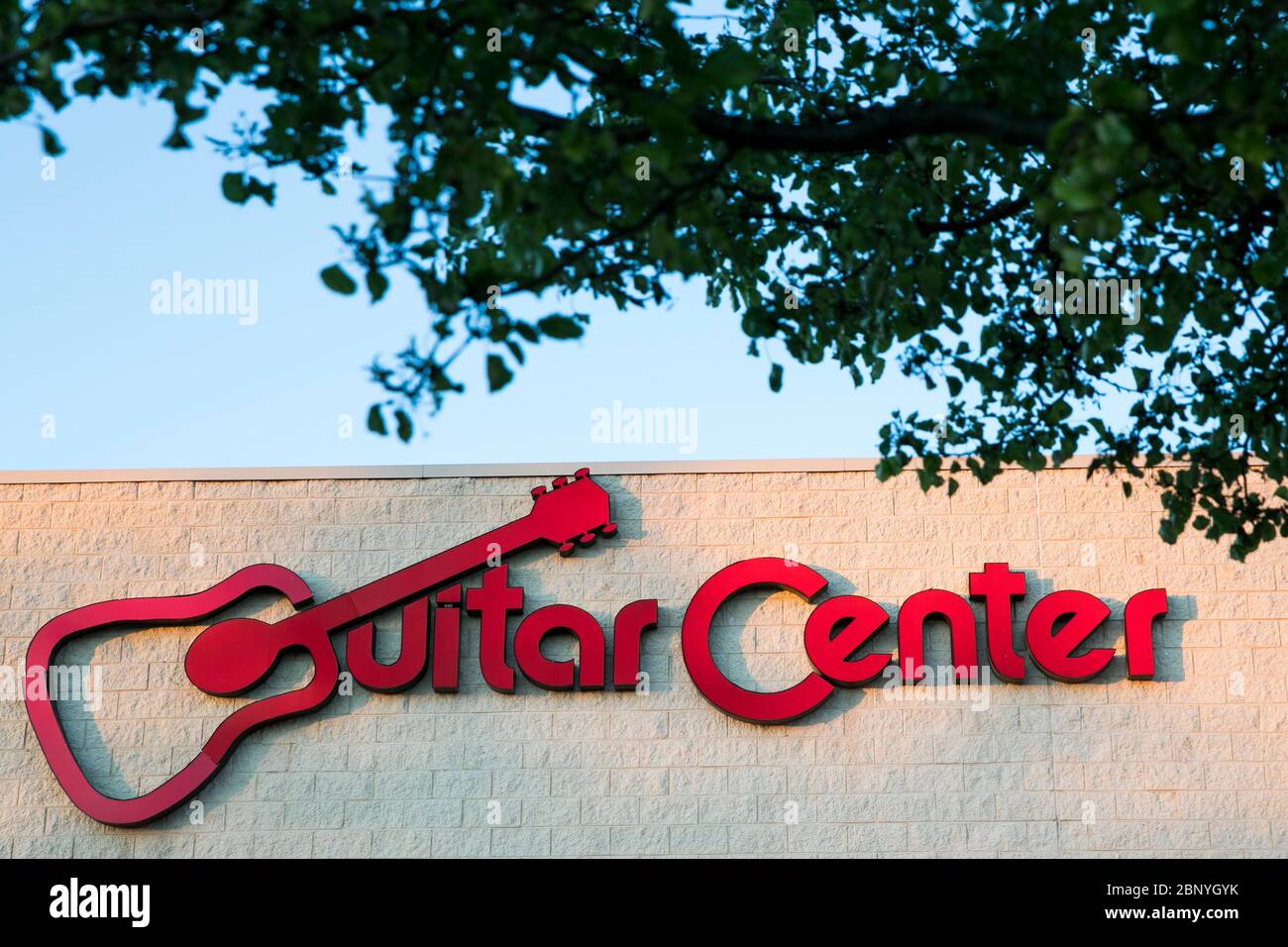 A logo sign outside of a Guitar Center retail store location in ...
