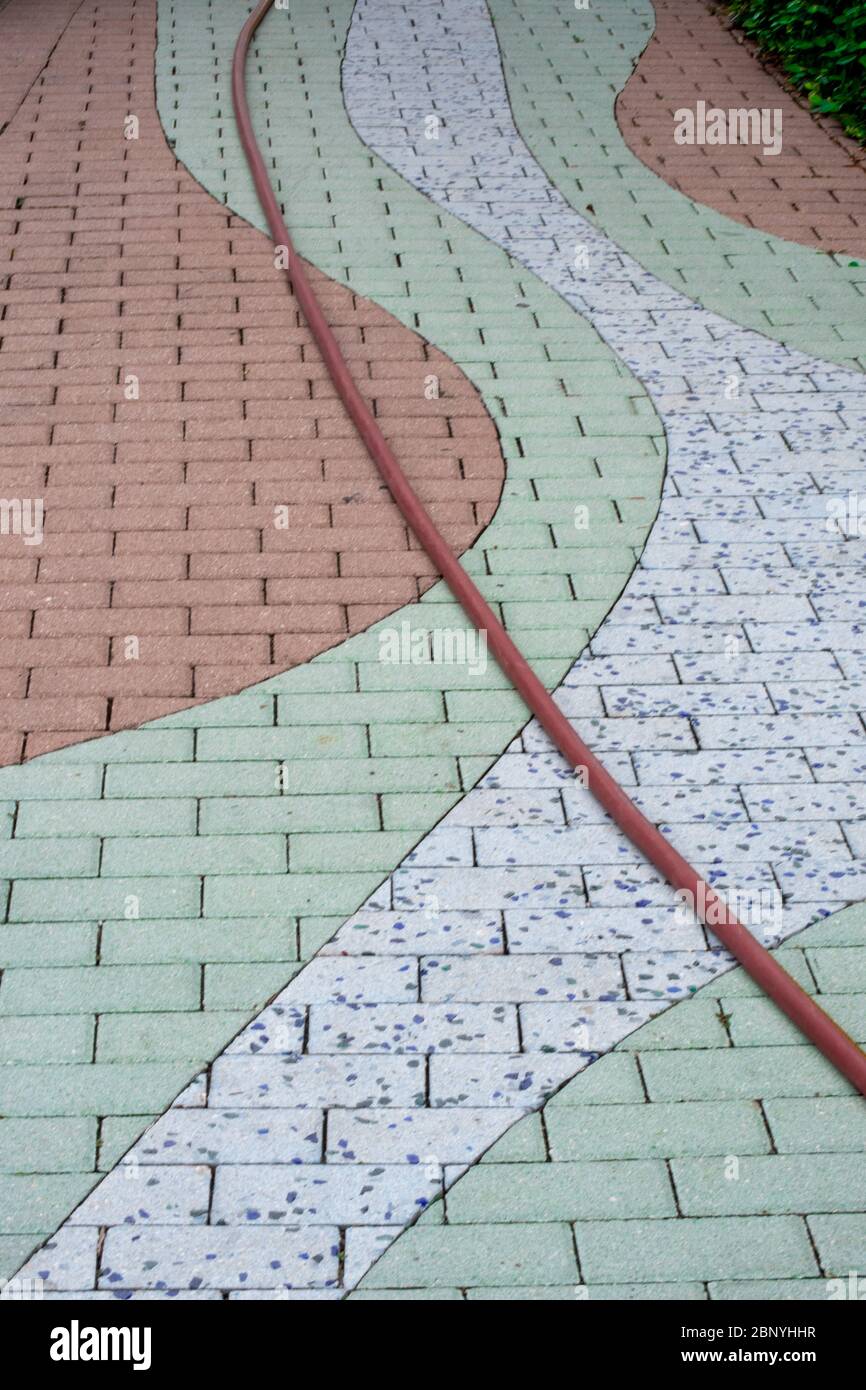 Water hose breaks up design of walkway Stock Photo - Alamy