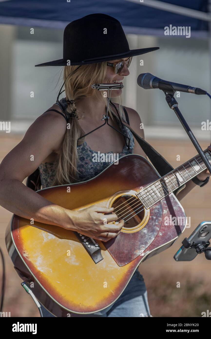 Pretty, blonde, female folk singer, playing guitar and singing at ...