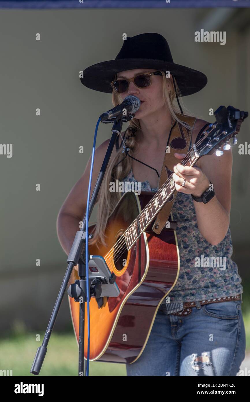 Pretty, blonde, female folk singer, playing guitar and singing at ...