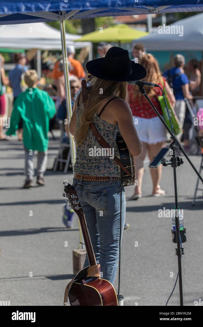 Pretty, blonde, female folk singer, playing banjoand singing at outdoor ...
